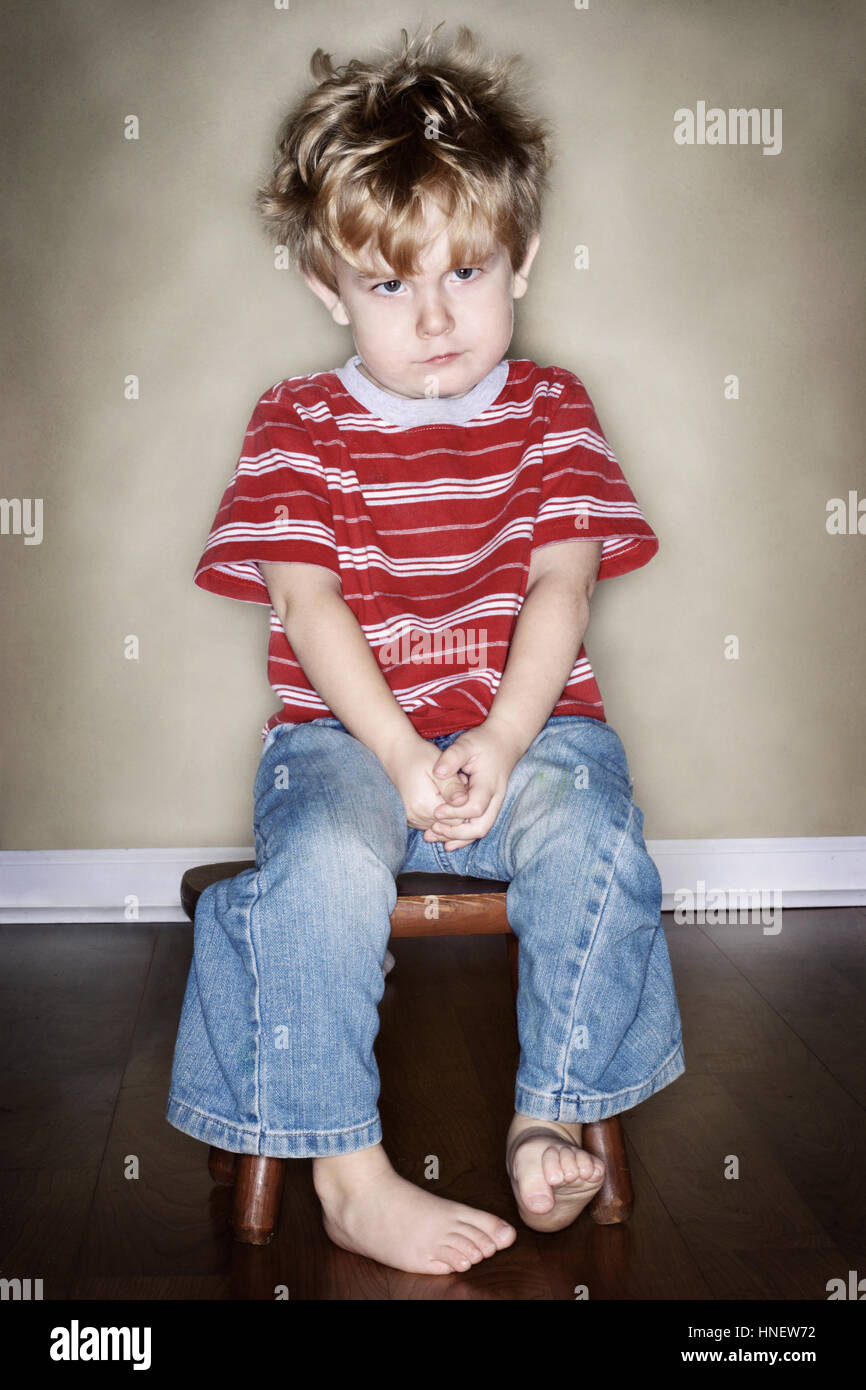 A sad young boy sits on a stool Stock Photo - Alamy
