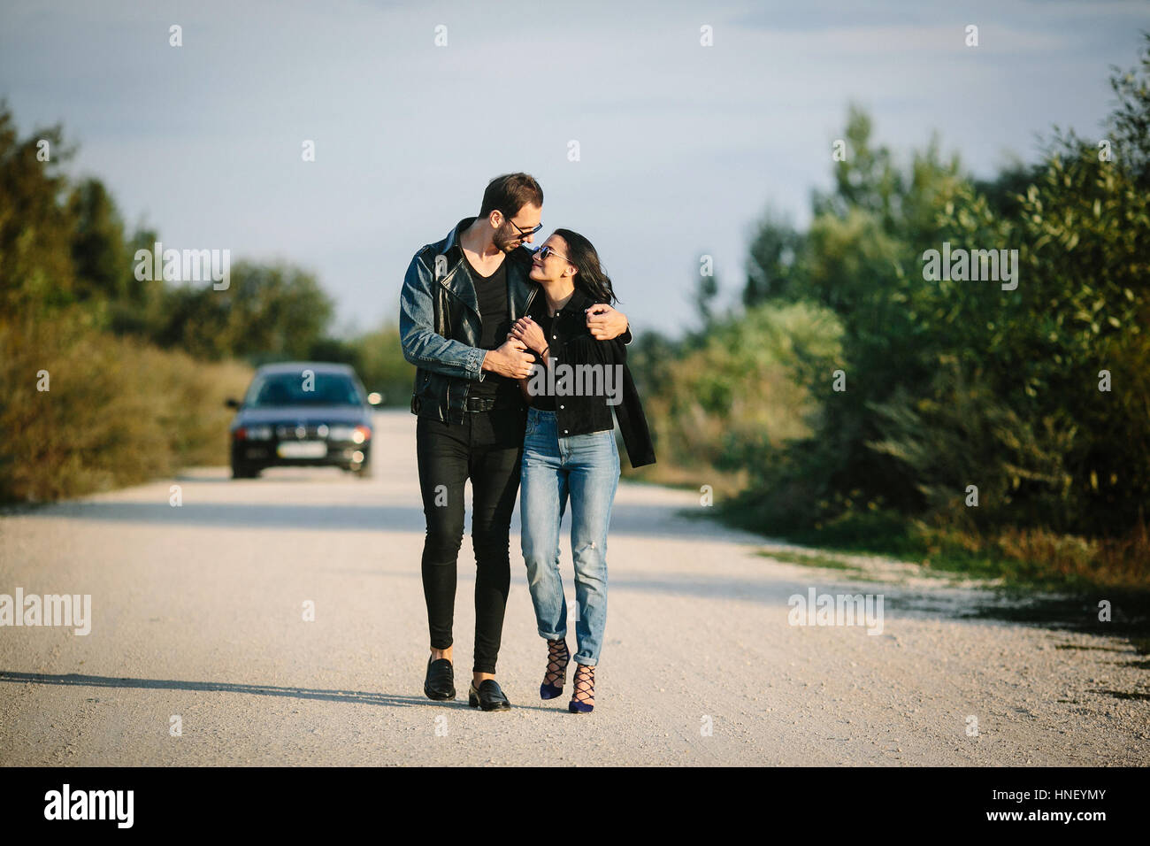 Young happy romantic couple walking along road Stock Photo - Alamy