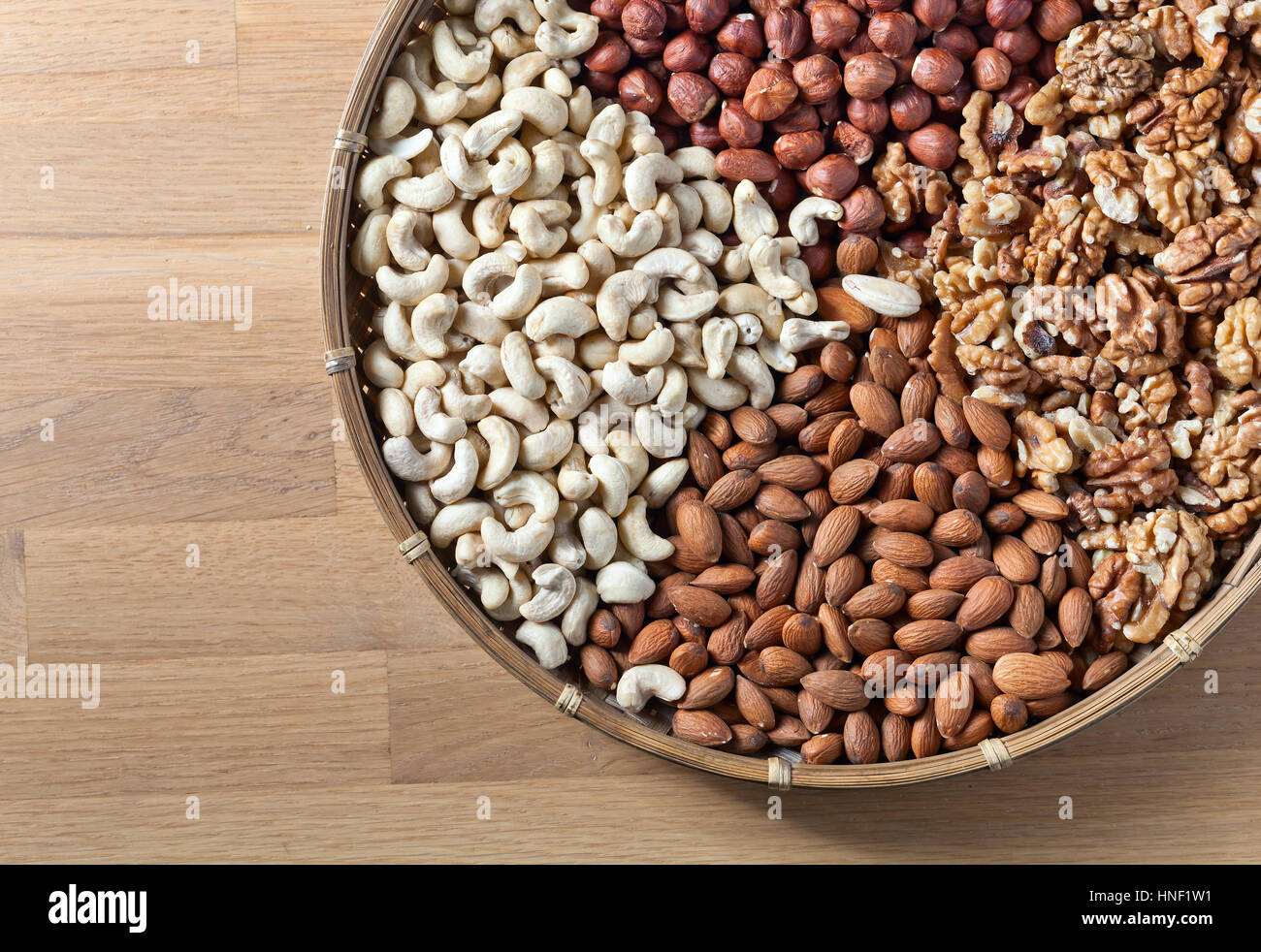 Different nuts in old wooden dish on a kitchen table Stock Photo - Alamy