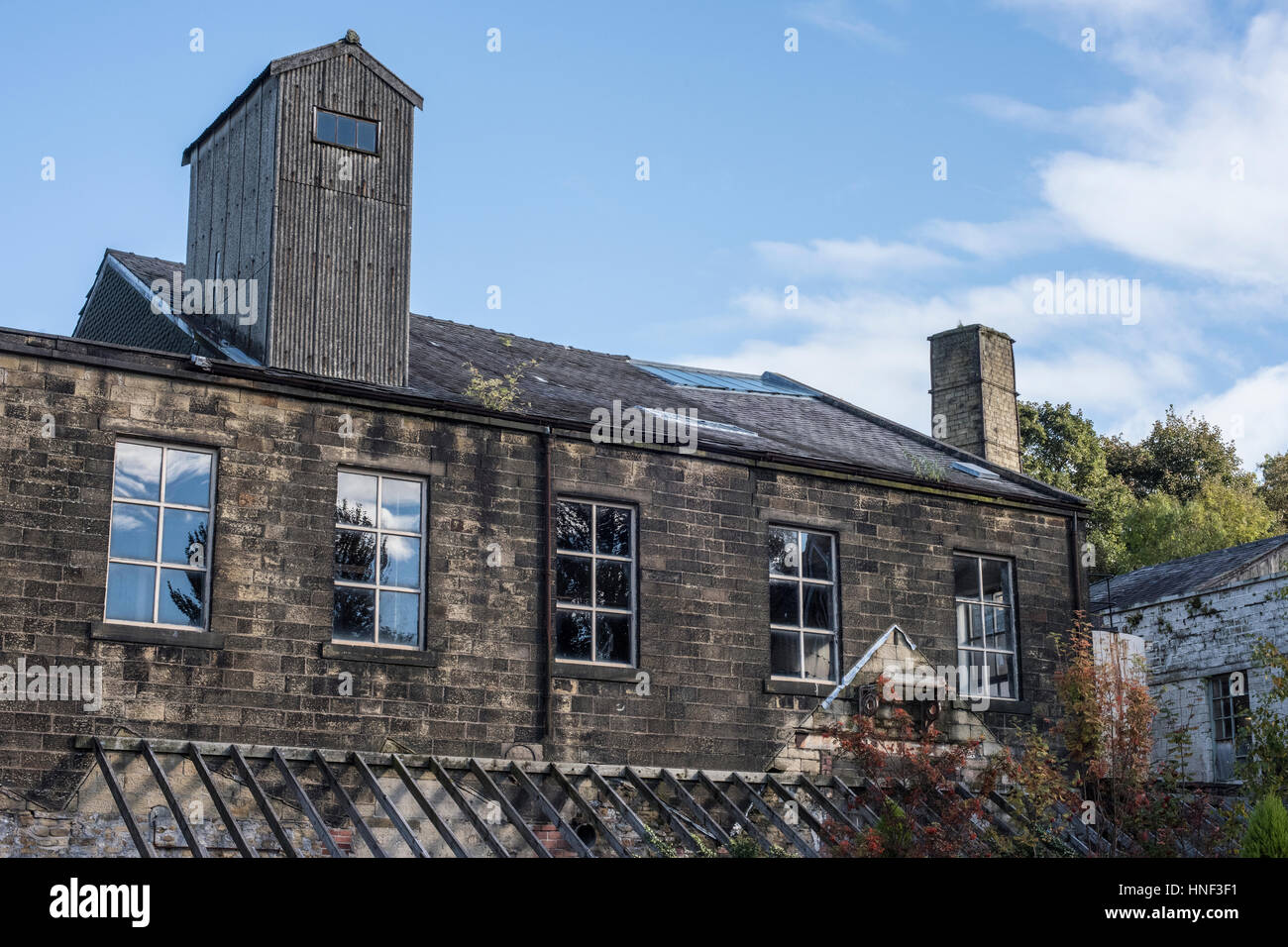Old cotton mill with timber tower and darkened sandstone walls ...