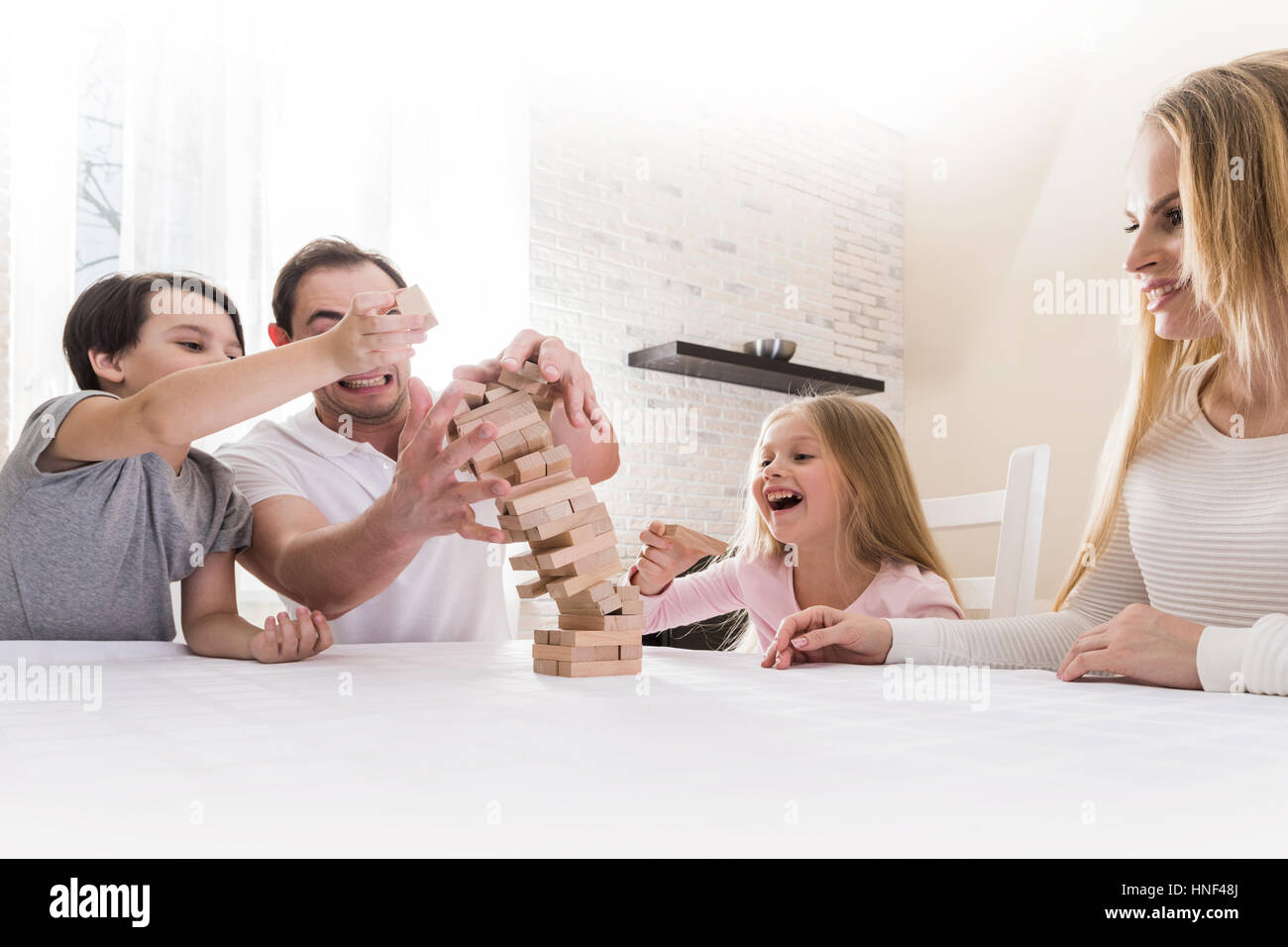 Happy family having fun playing Jenga, tower collapsing Stock Photo - Alamy