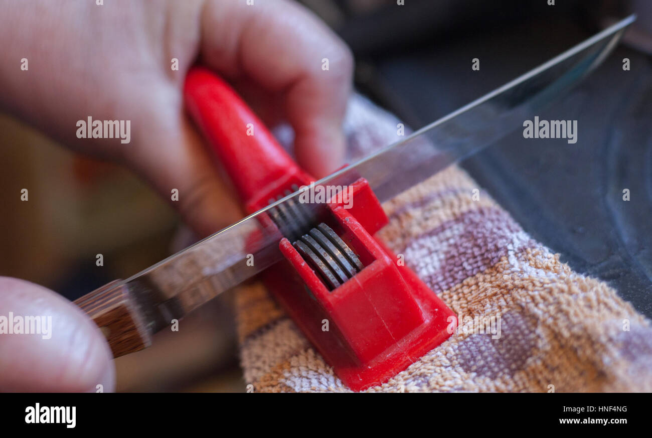 Woman's hand sharpening knife on red knife sharpener Stock Photo - Alamy