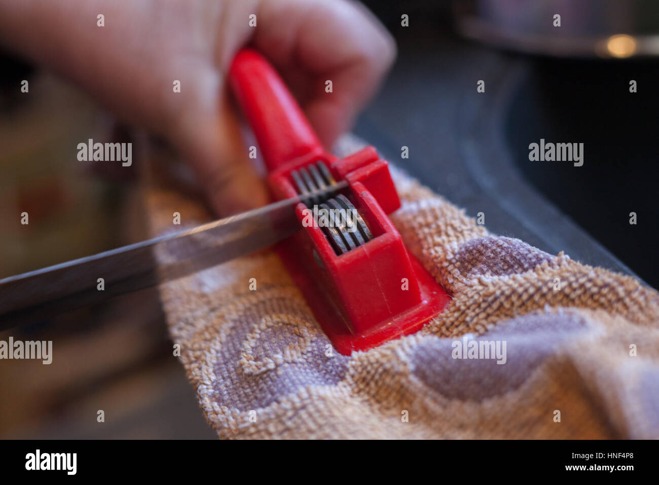 Woman's hand sharpening knife on red knife sharpener Stock Photo - Alamy