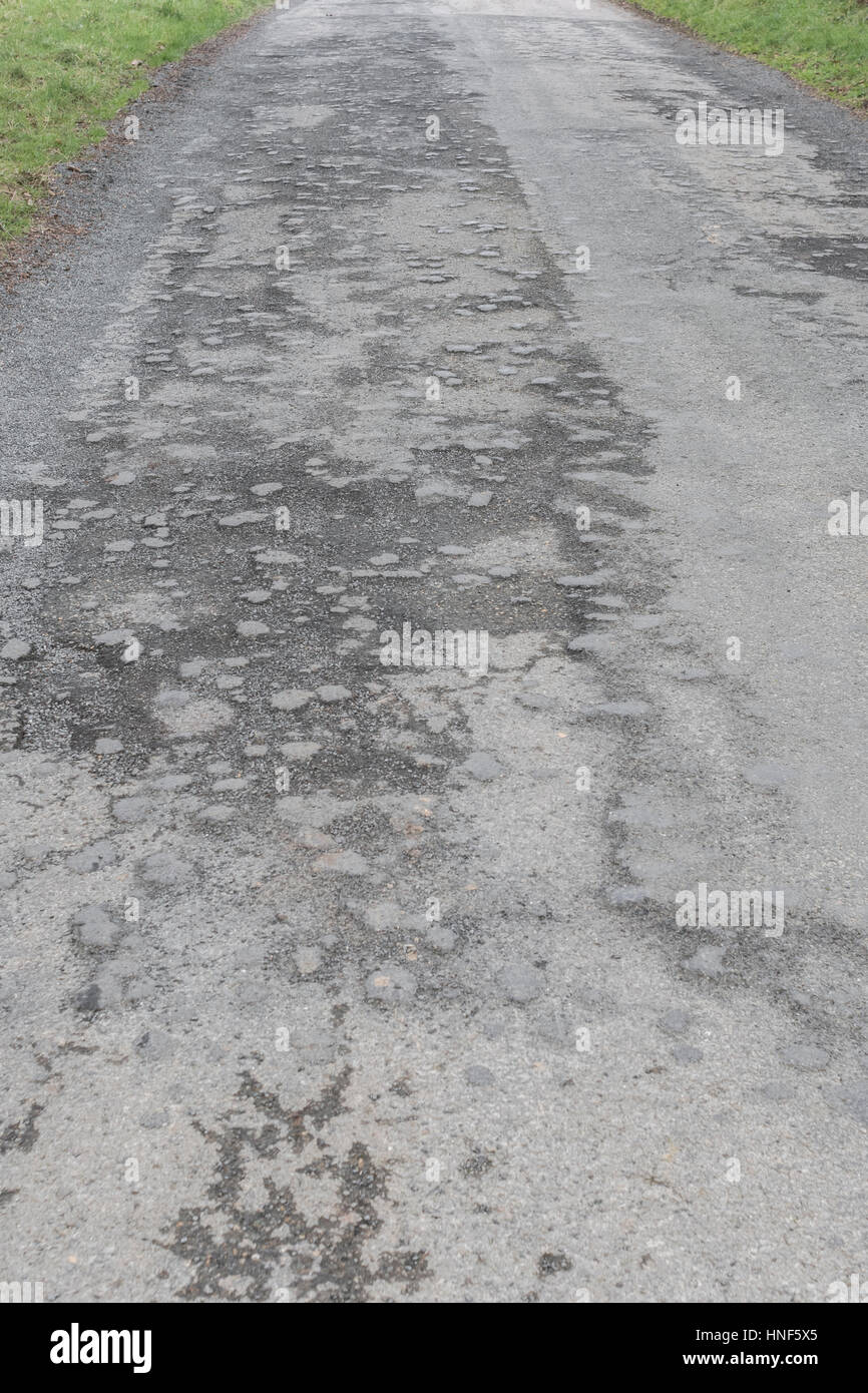 Badly repaired country / rural road in mid-Cornwall. Old tarmac surface ...