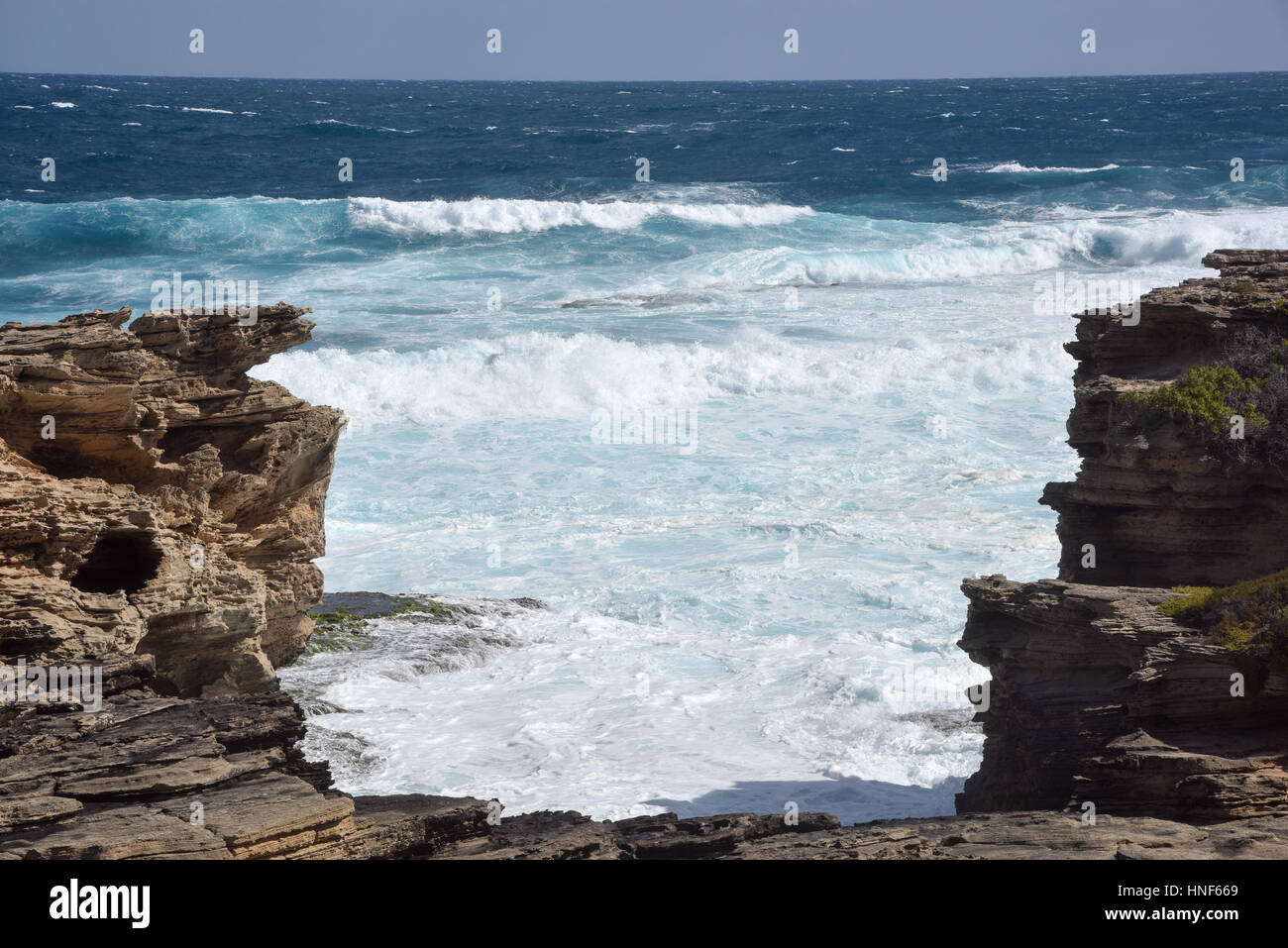 Foamy Indian Ocean waves rushing limestone inlet at Cape Vlamingh at ...