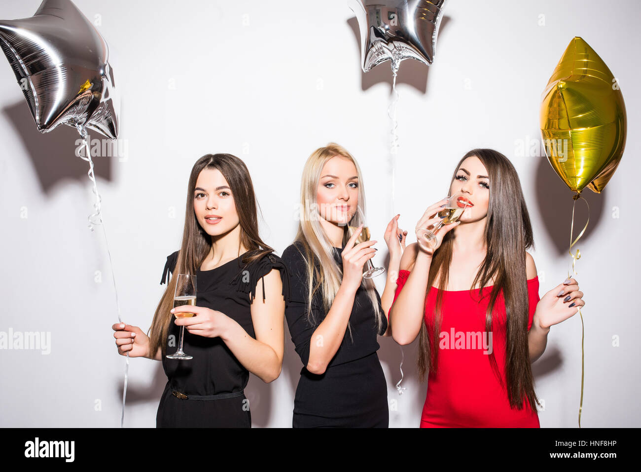 Cheerful young women drinking champagne, talking and laughing with ...