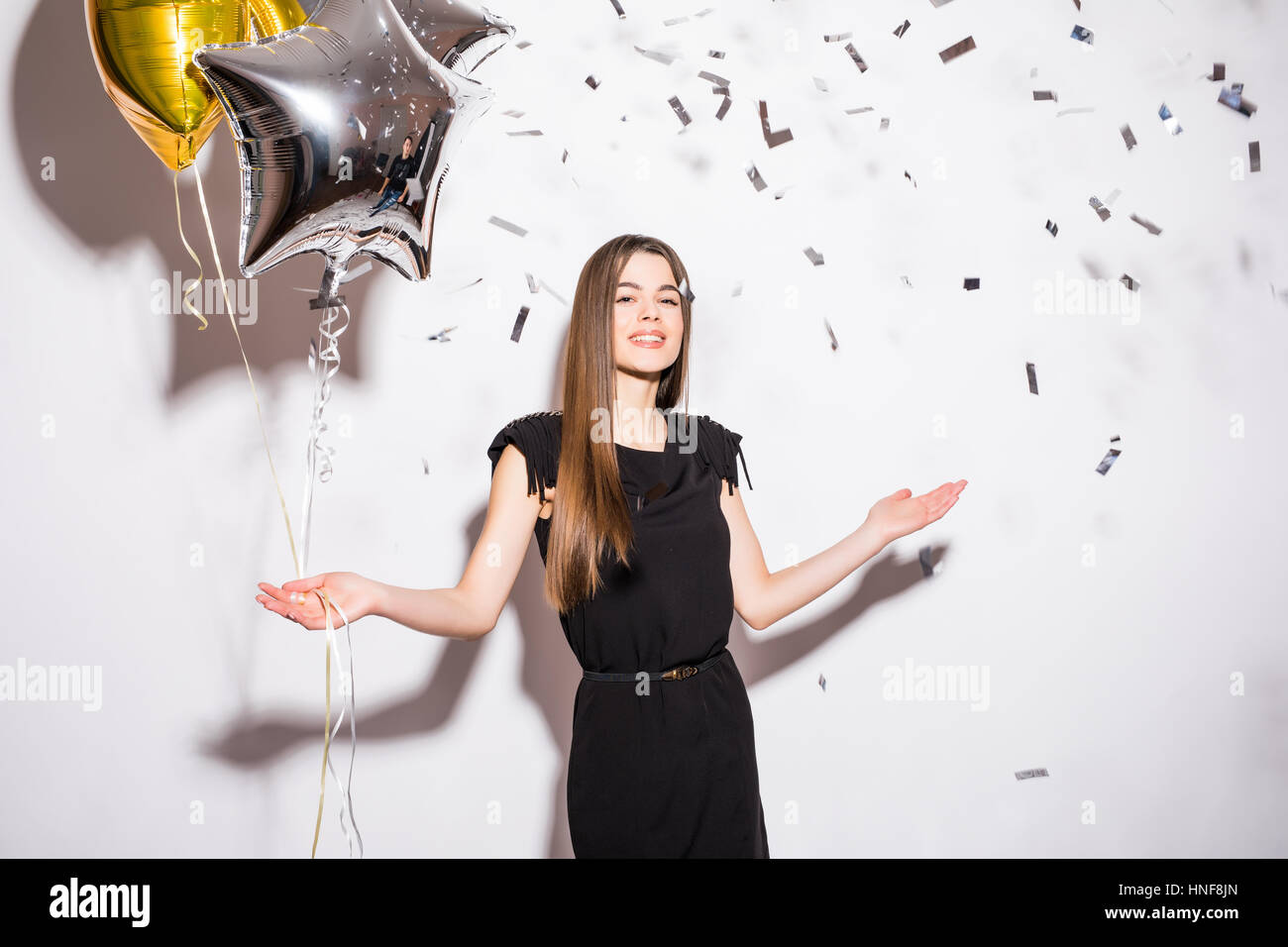 young woman holding star balloon with fly confetti on party over white ...