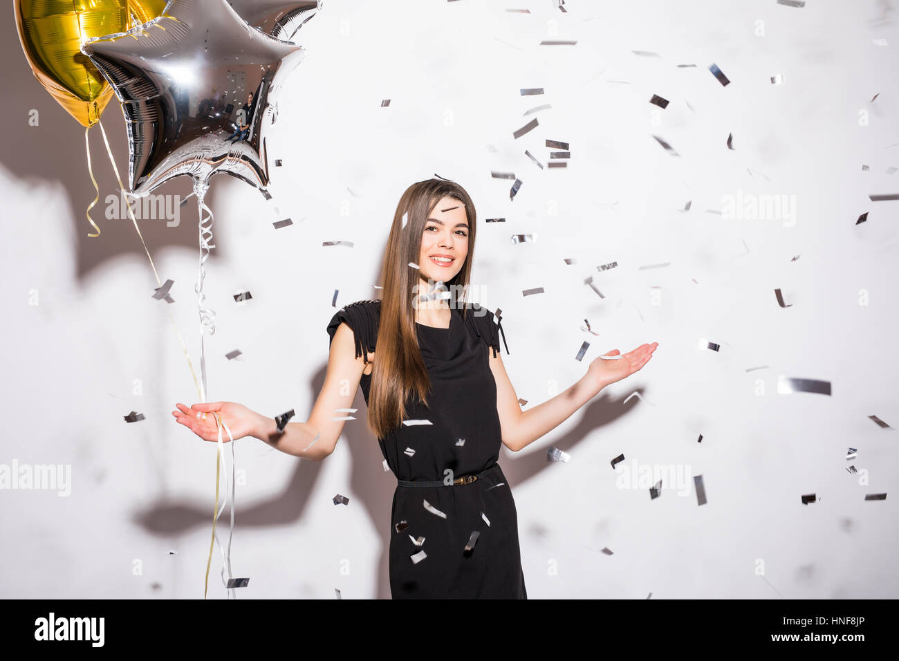 young woman holding star balloon with fly confetti on party over white ...