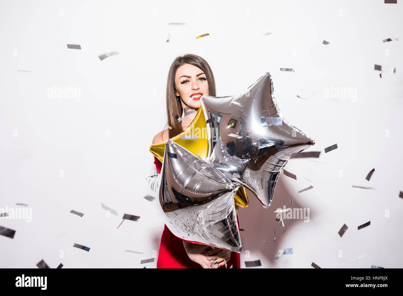 Young woman in red dress holding star balloon with fly confetti at ...