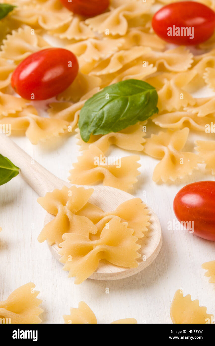 raw farfalle bow-tie pasta with tomato and basil Stock Photo - Alamy