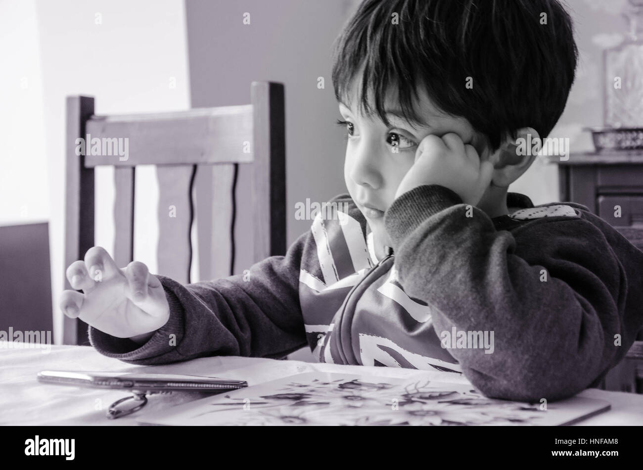 A young child is bored as he sits at the dining table Stock Photo - Alamy