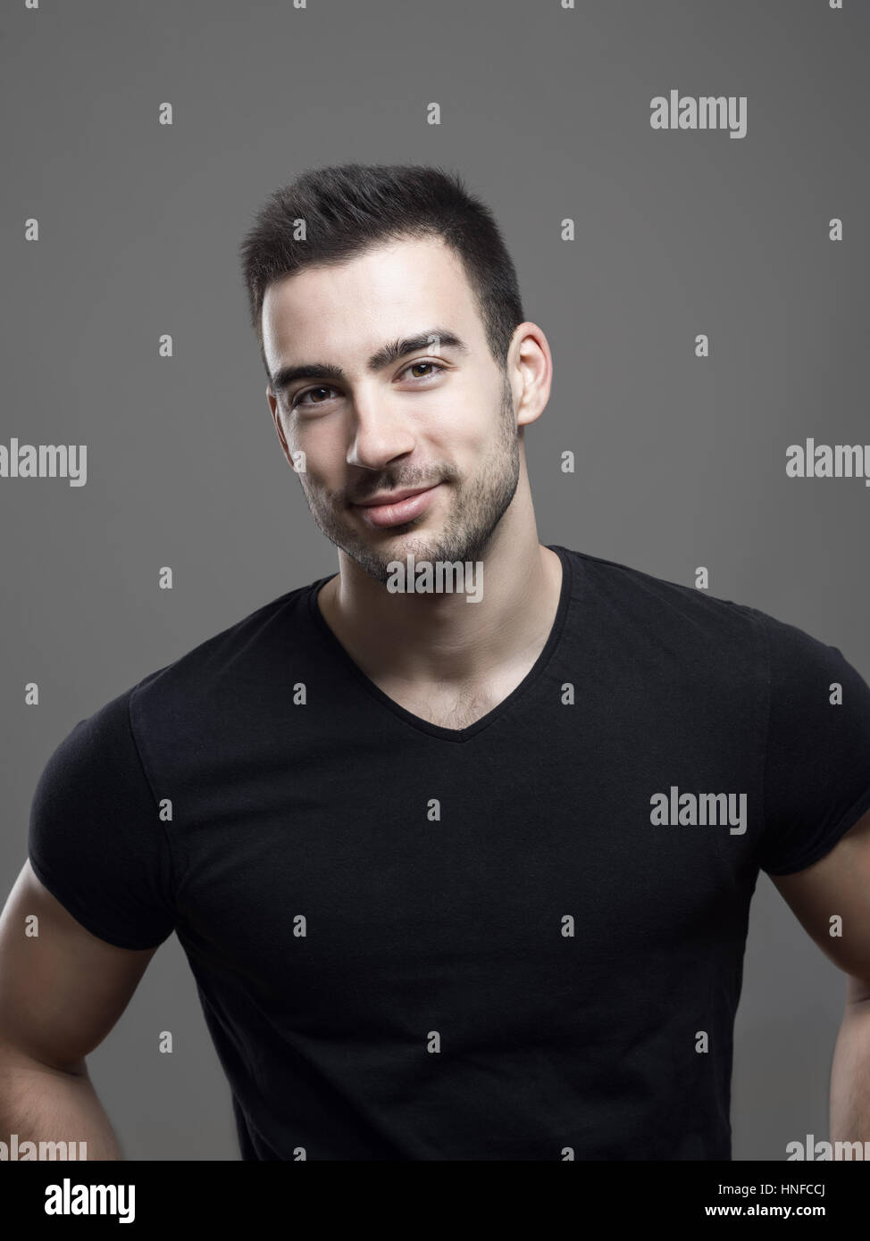 Moody portrait of confident young smiling fitness male model in blank ...