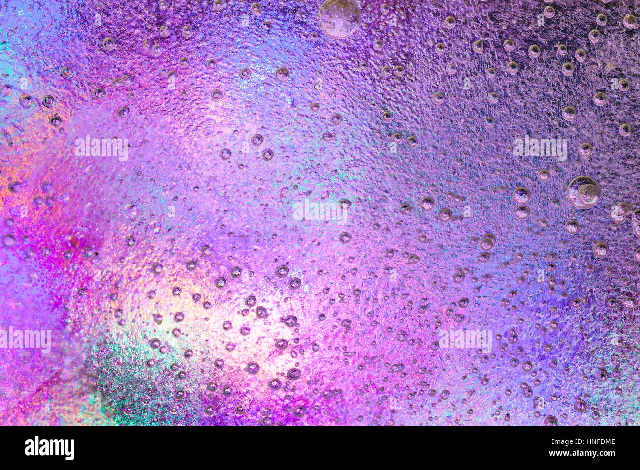 Pink frozen ice with beautiful colours below. Large and small trapped ...