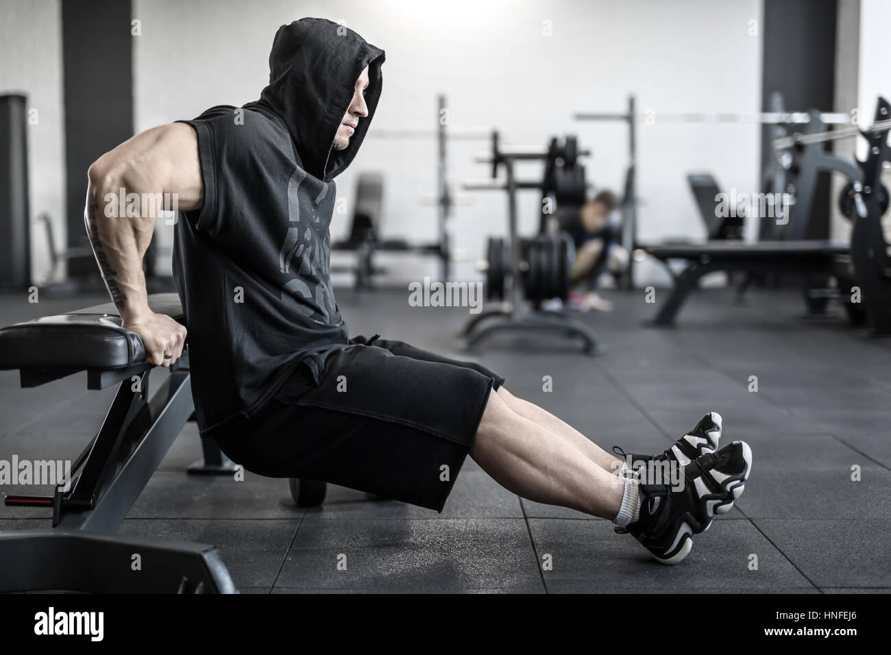 Strong man with heavy muscles does lifting on the bench in the gym. He ...