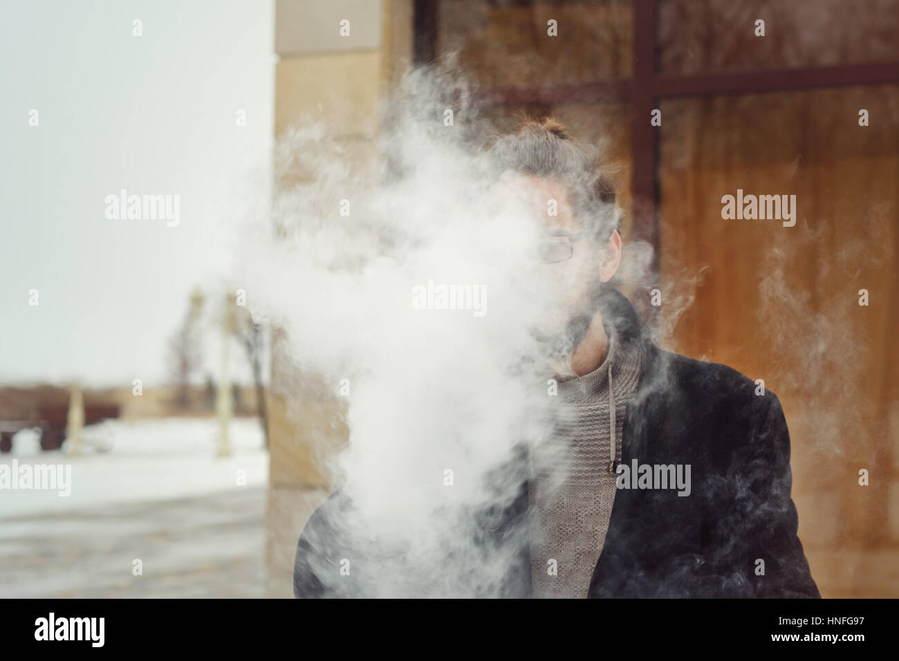 The man in the smoke. He smokes electronic cigarette. Evaporate Stock ...