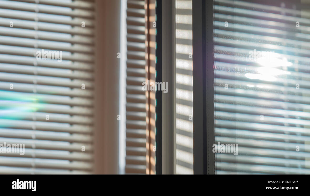 The sun shining through the blinds and are reflected in the window ...