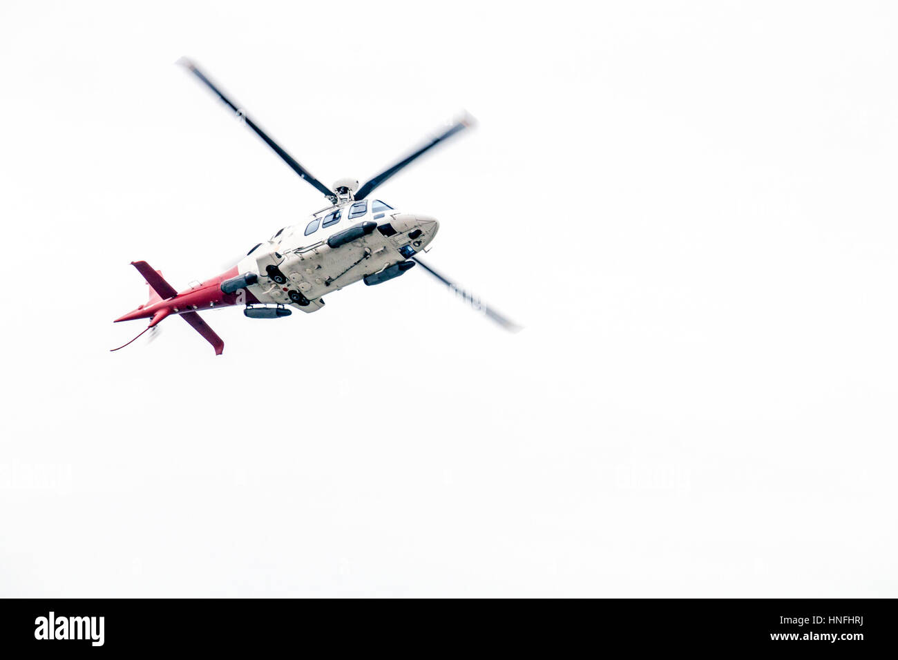Under view of airborne helicopter isolated against white overcast sky ...