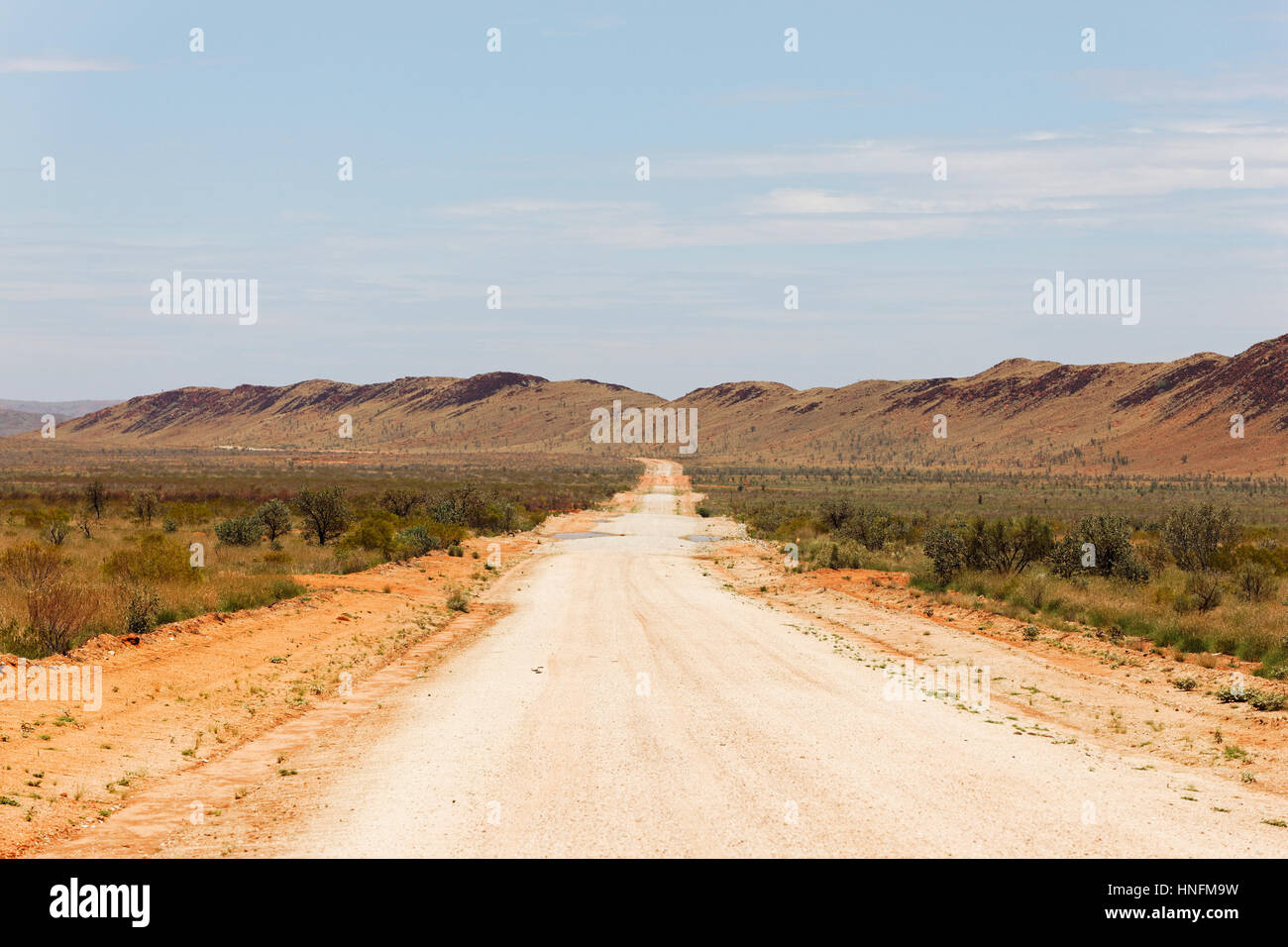 Long white gravel dirt road in outback landscape, Pilbara, Western ...