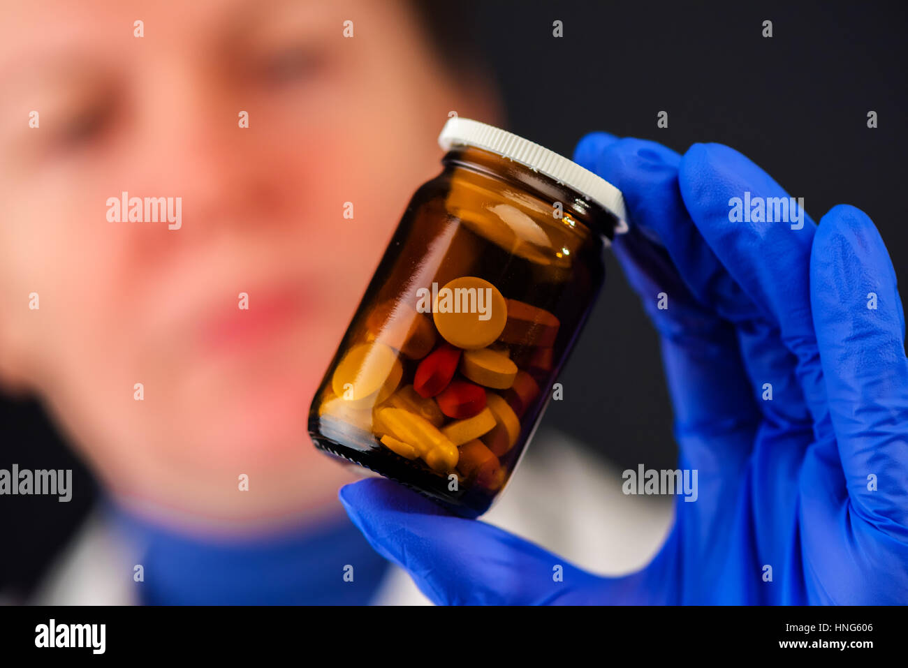 Female doctor holding unlabeled bottle of various pills and medication ...