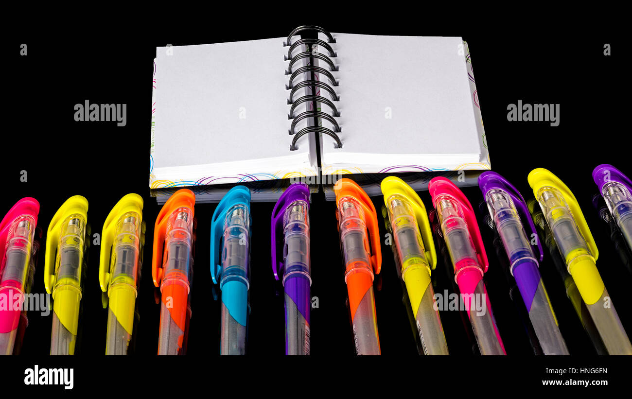 Many pens border a small pad of paper Stock Photo - Alamy
