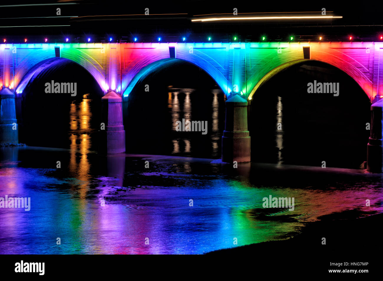 Rainbow bridge illuminated by glowing colored lights at night with ...