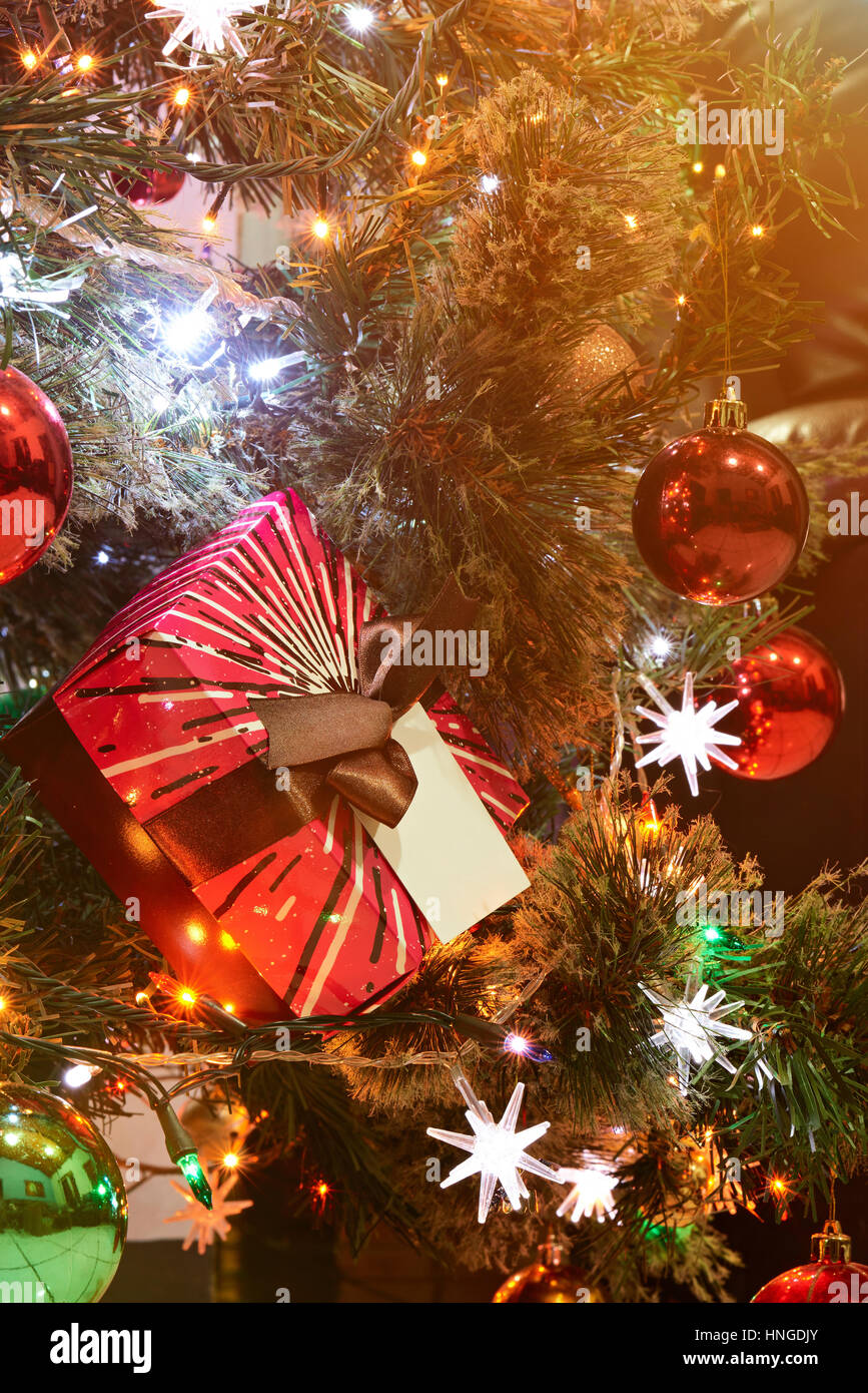 red gift present with christmas tree background with balls and lights ...