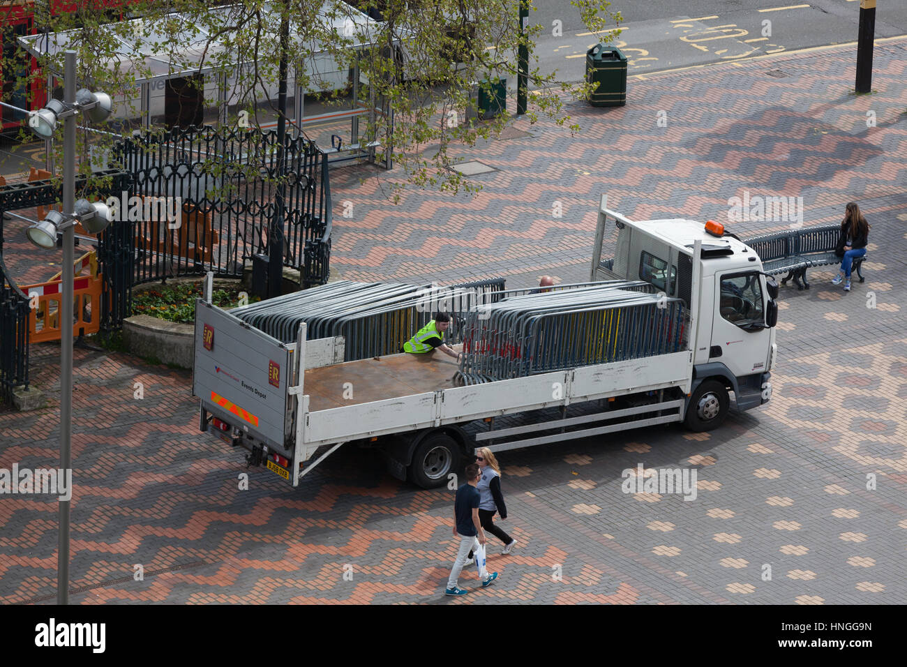 Workers loading metal barriers on the back of a flat-bed truck in ...