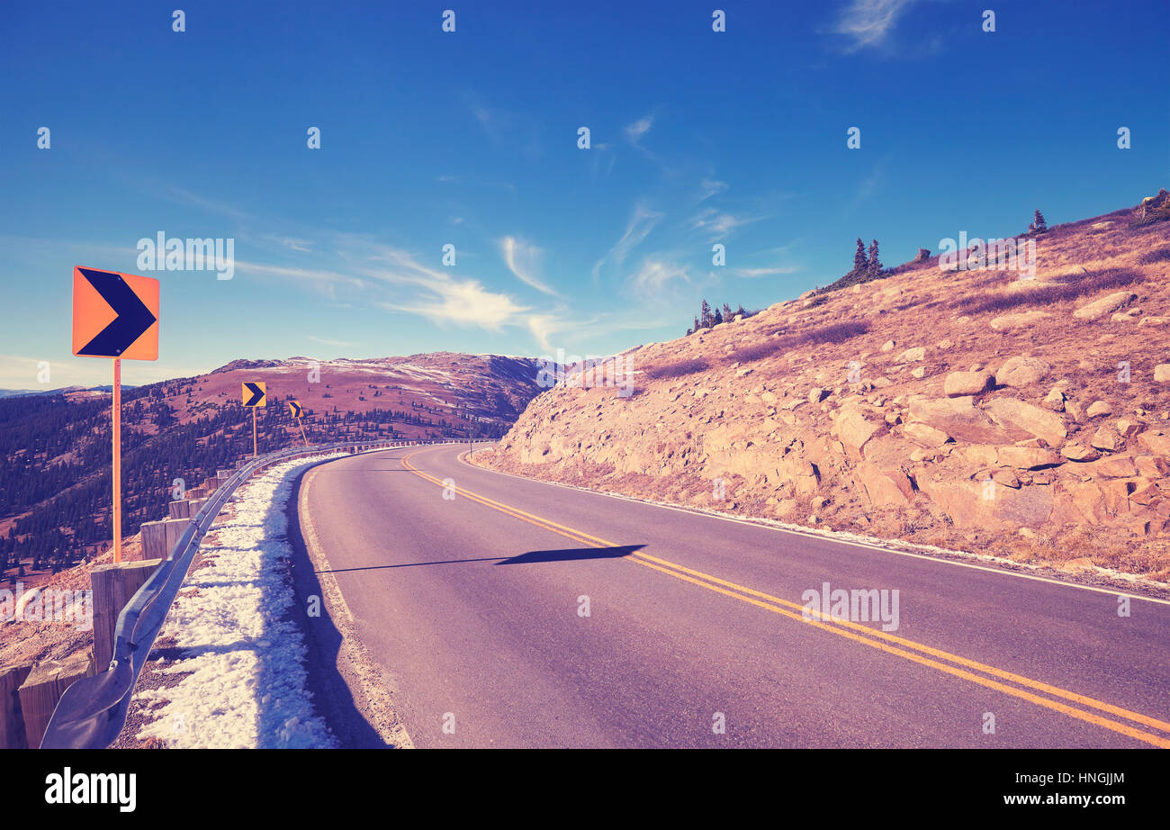 Vintage toned mountain asphalt road turn, travel warning concept ...