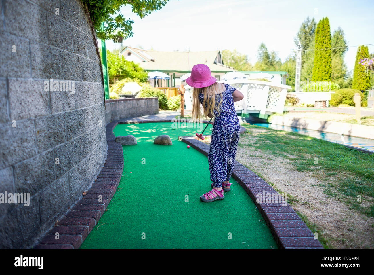 Young girl playing mini-golf or crazy golf at a mini-golf course in ...