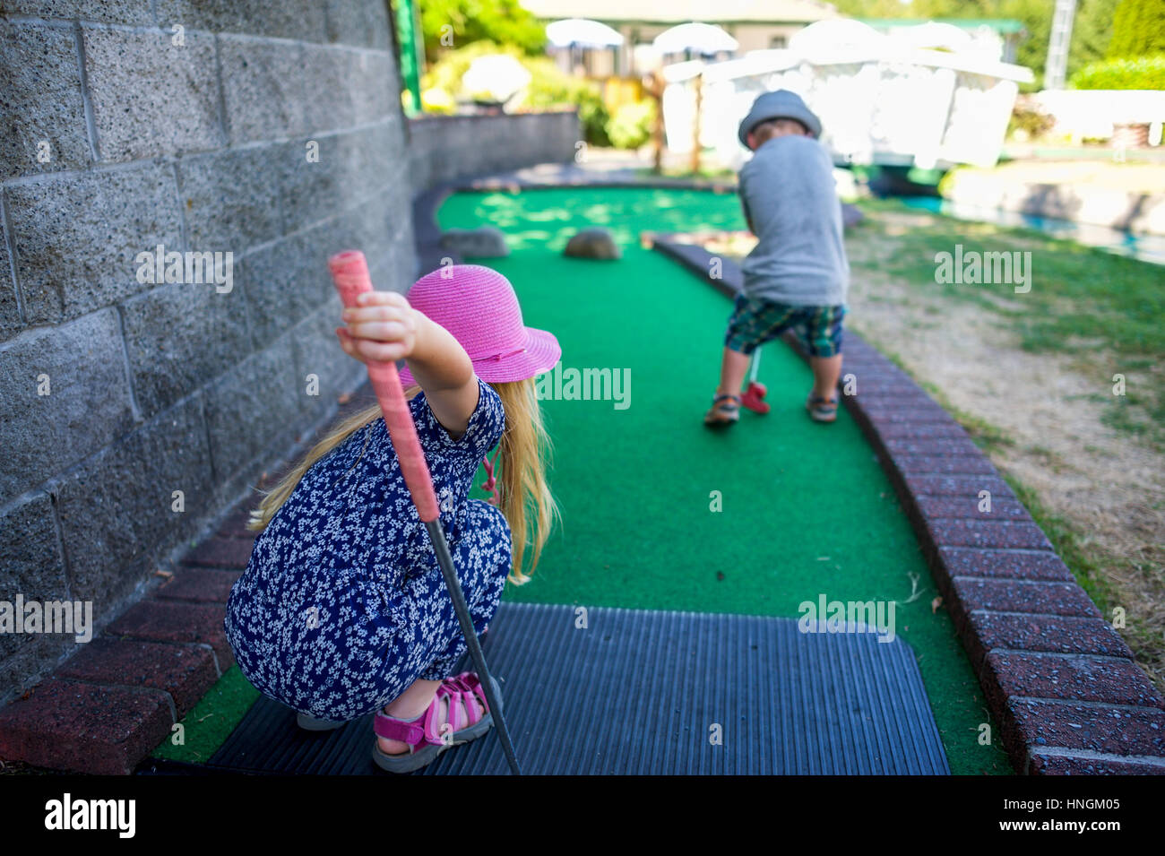 Two young children playing mini-golf or crazy golf at a mini-golf ...