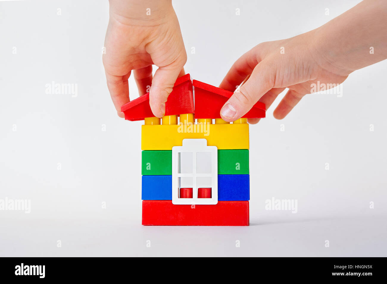 The hand establishes a toy roof on plastic cubes. hand putting a roof ...