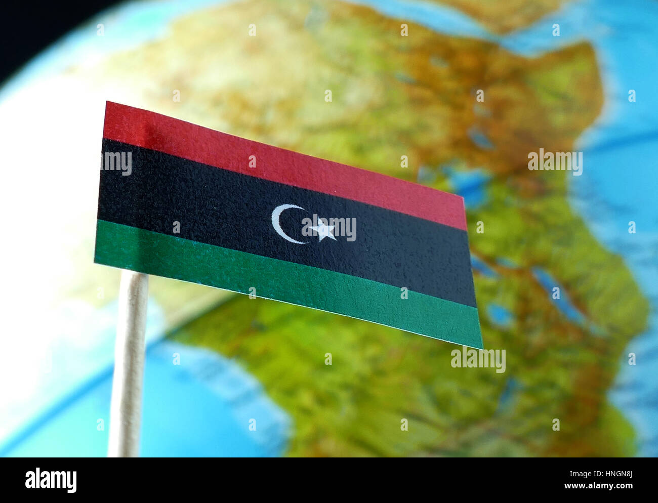 Libya flag with a globe map as a background macro Stock Photo - Alamy