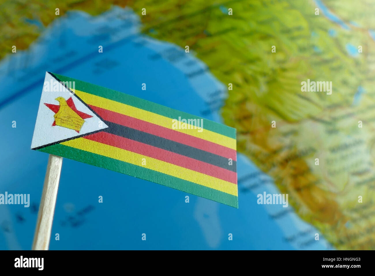 Zimbabwe flag with a globe map as a background macro Stock Photo - Alamy