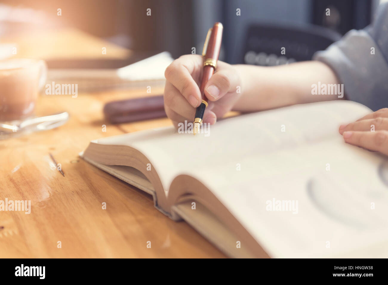 woman's hand reading book with pen, tablet and notebook on wooden table ...