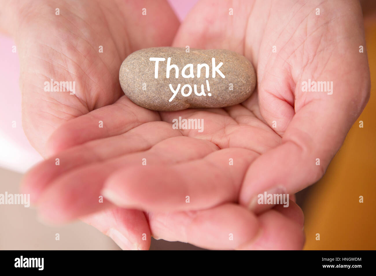 closeup of womans hands holding a stone with the words thank you ...