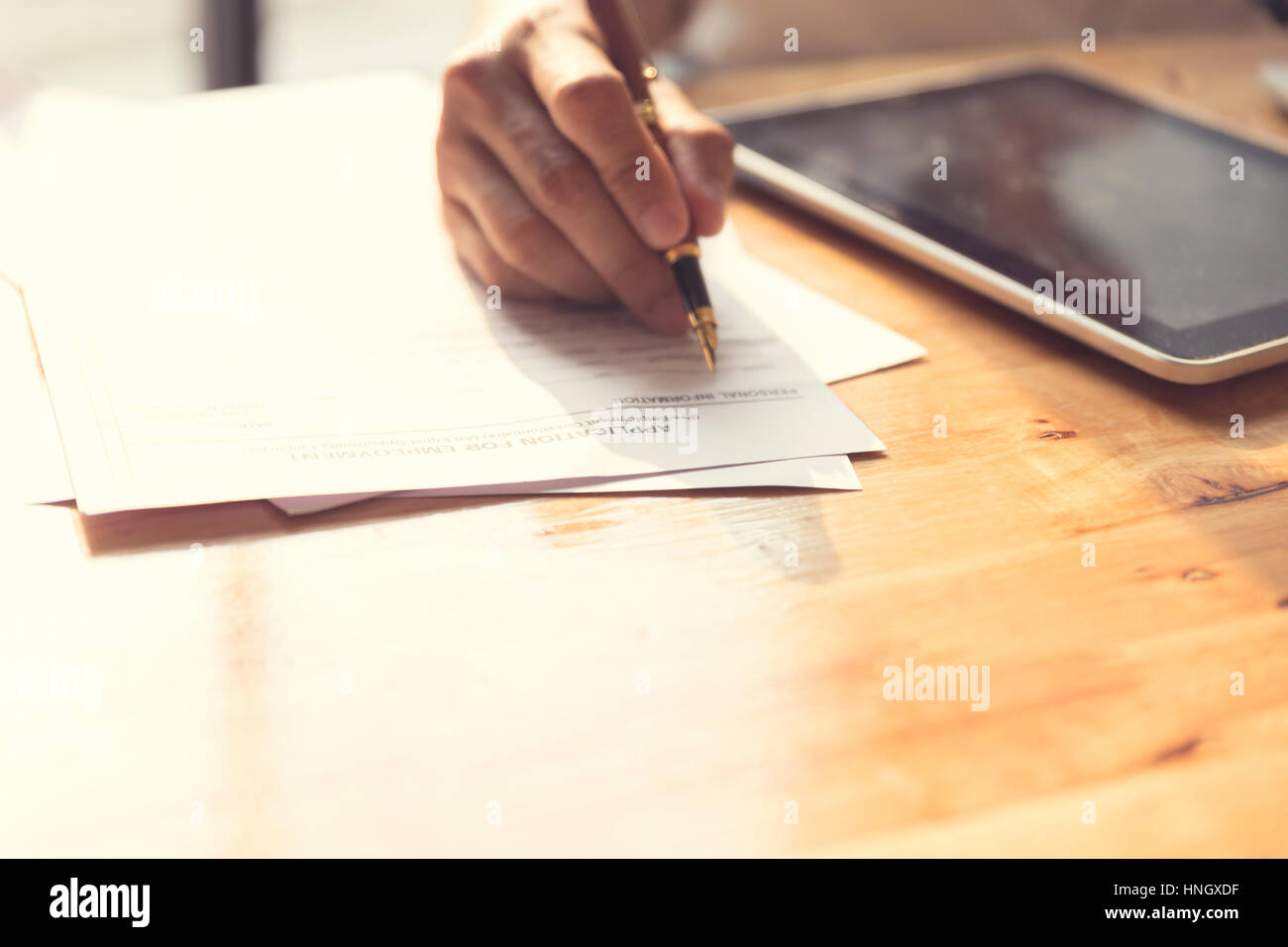 man's hand signing application form with tablet on wooden table ...