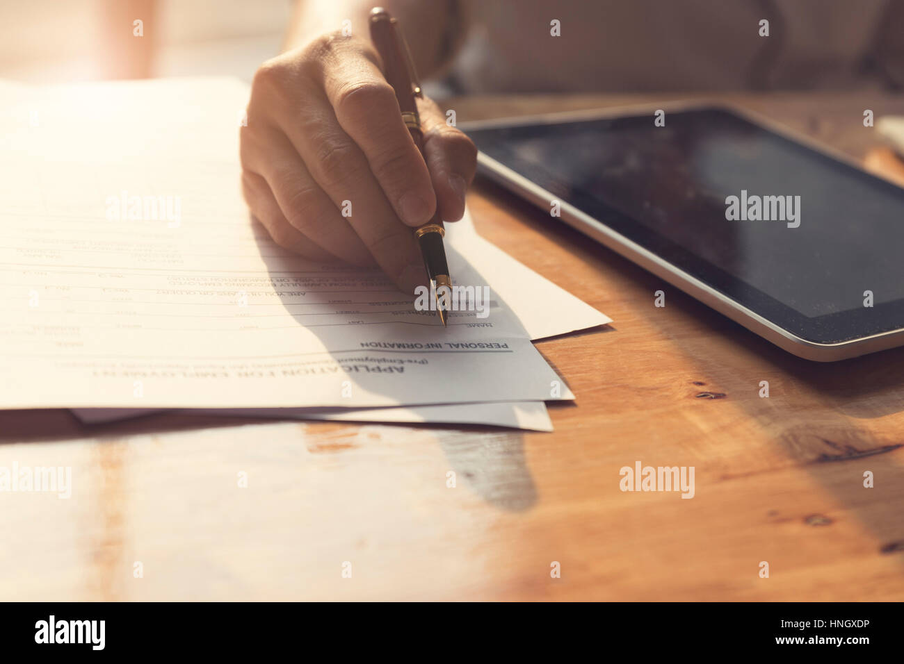 man's hand signing application form with tablet on wooden table ...