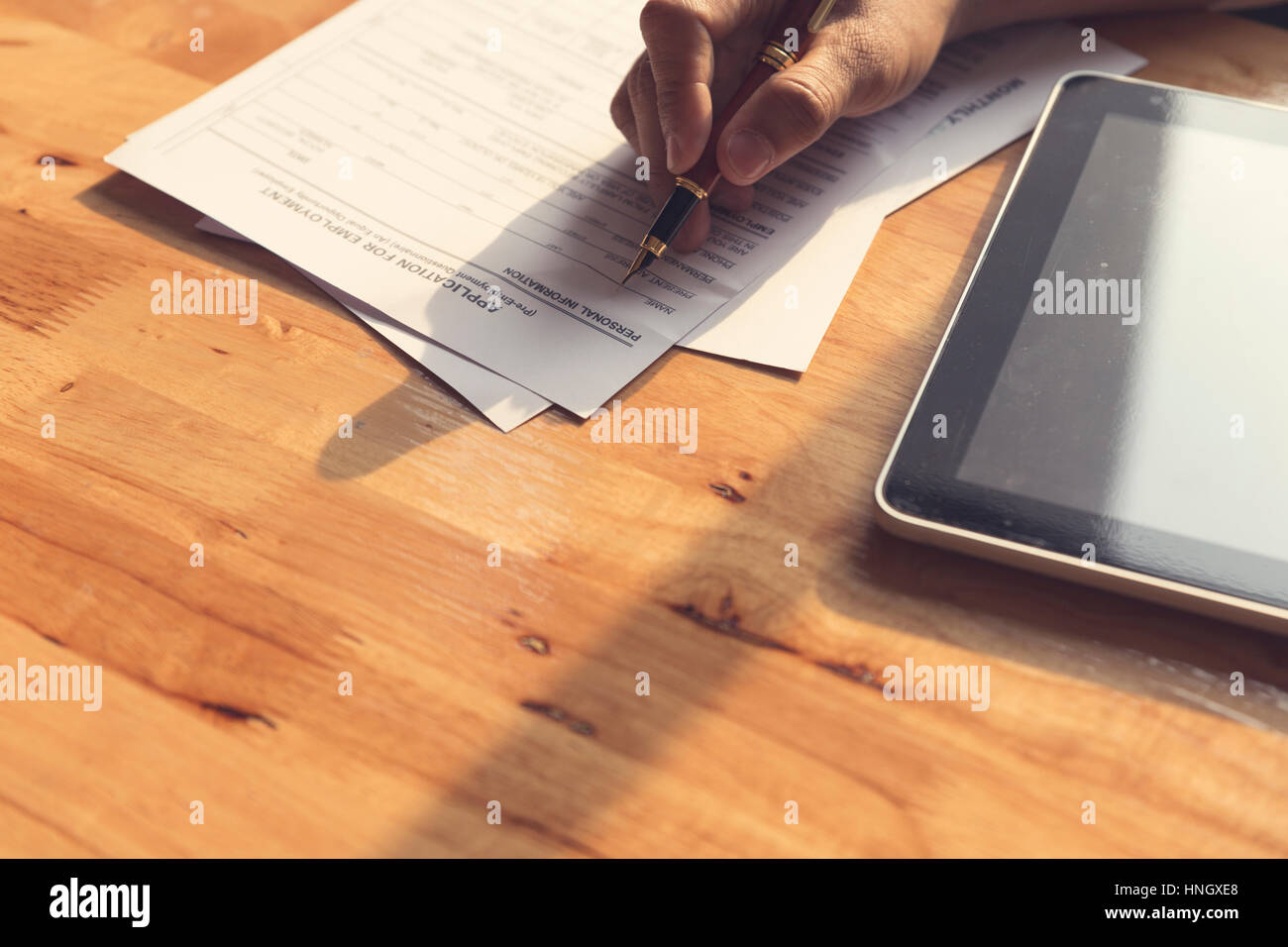 man's hand signing application form with tablet on wooden table ...