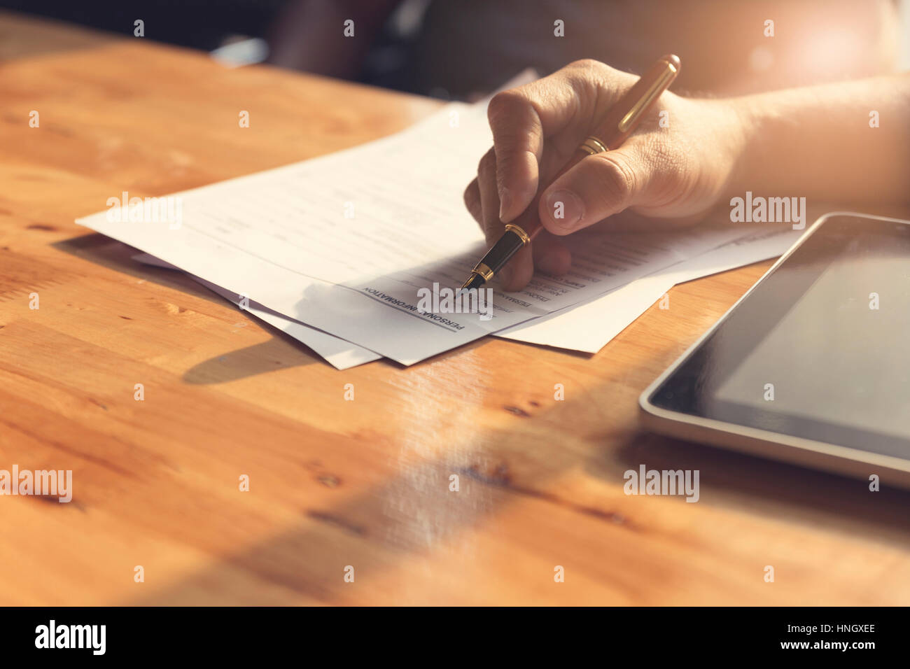 man's hand signing application form with tablet on wooden table ...