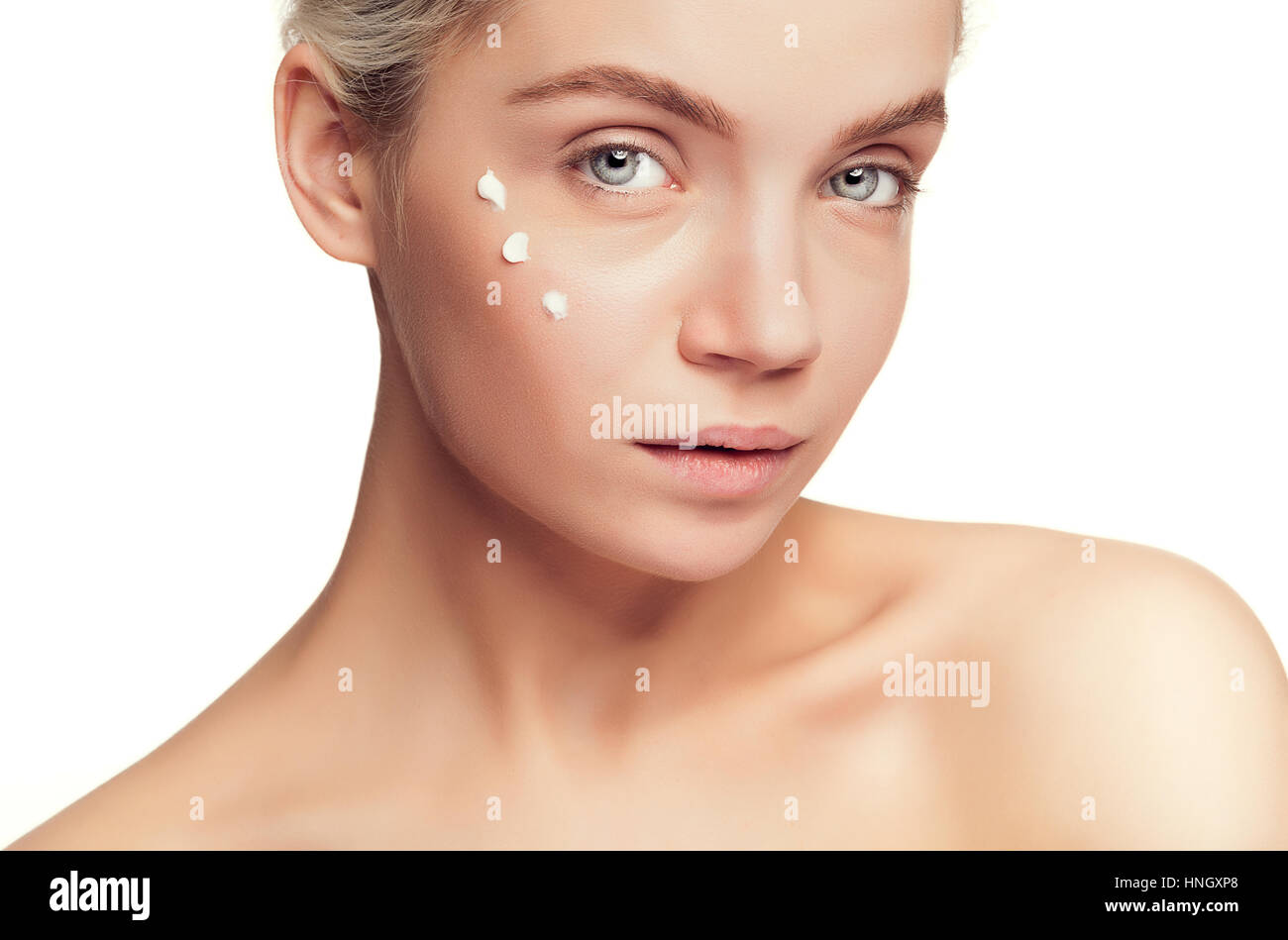 Young woman with drops of cream on her face isolated over white ...