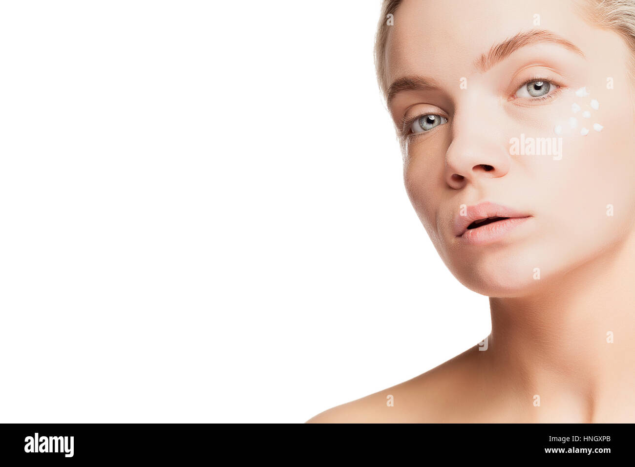 Woman with drops of cream on her face on white background in studio ...
