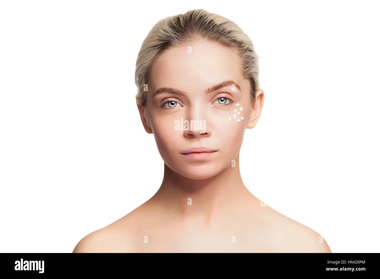 Young woman with cream drops on face on white background in studio ...