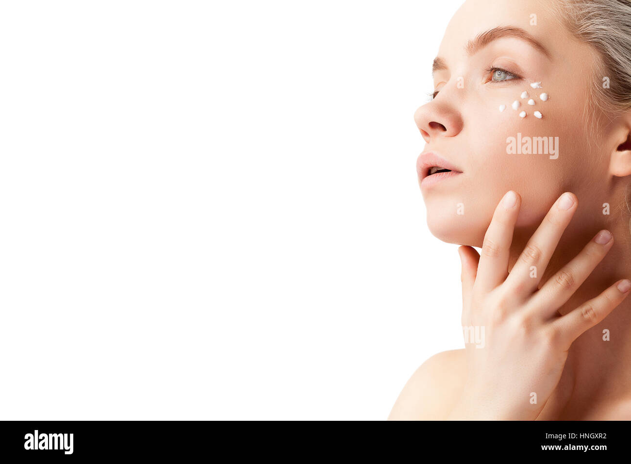 Gorgeous woman with cream drops on face on white background in studio ...