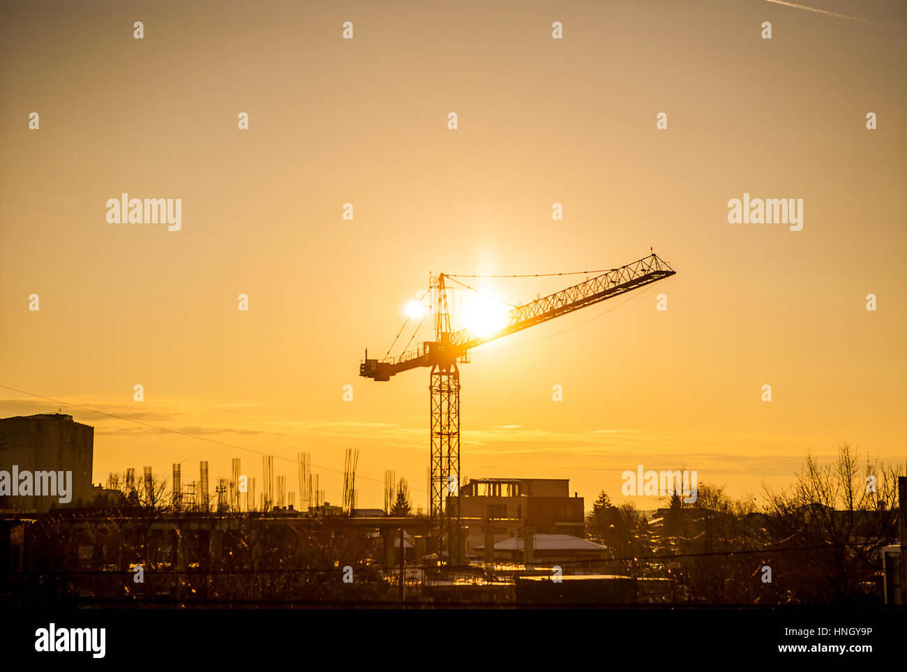 Sunset through a crane in industrialized area of city. Silhouette of a ...