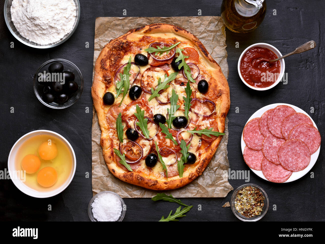 Homemade pizza and ingredients on dark background, top view Stock Photo ...
