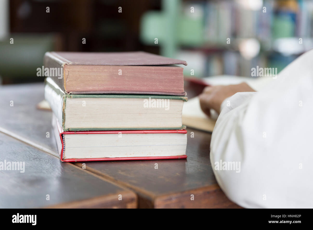 man reading book with textbook stack on wooden desk in library Stock ...