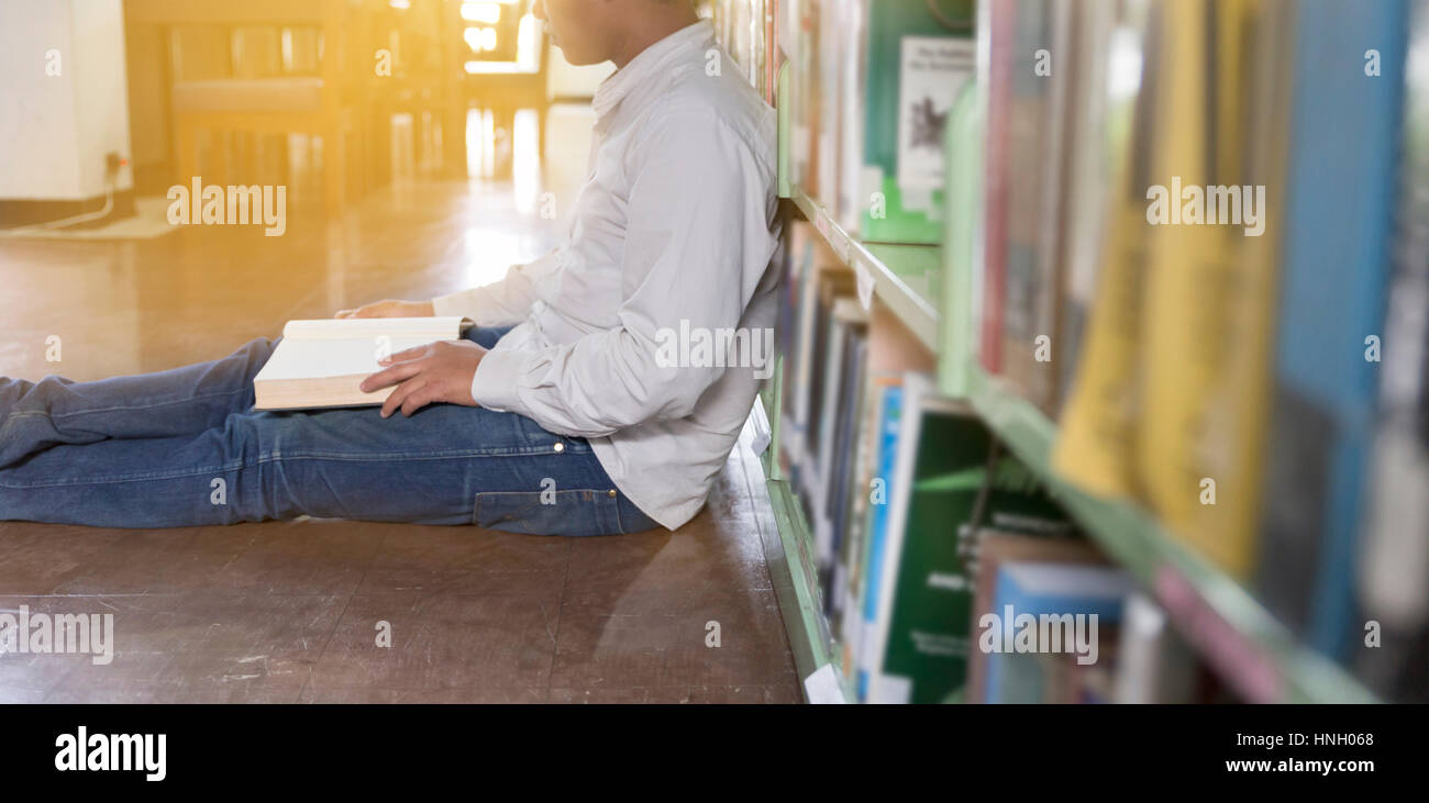 man sitting and reading book on floor in aisle in library Stock Photo ...