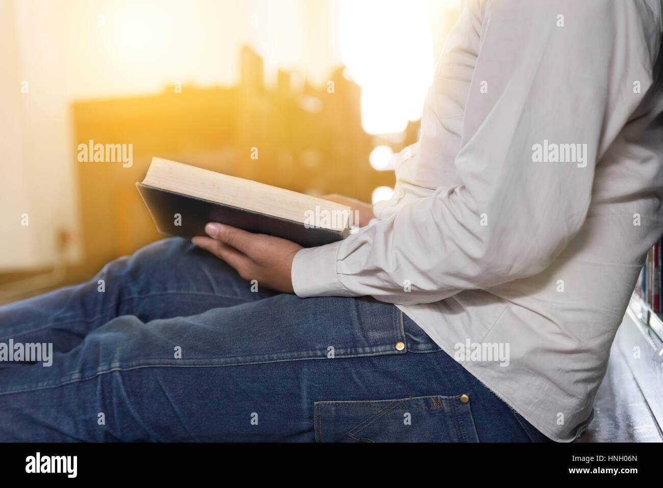 man sitting and reading book on floor in aisle in library Stock Photo ...