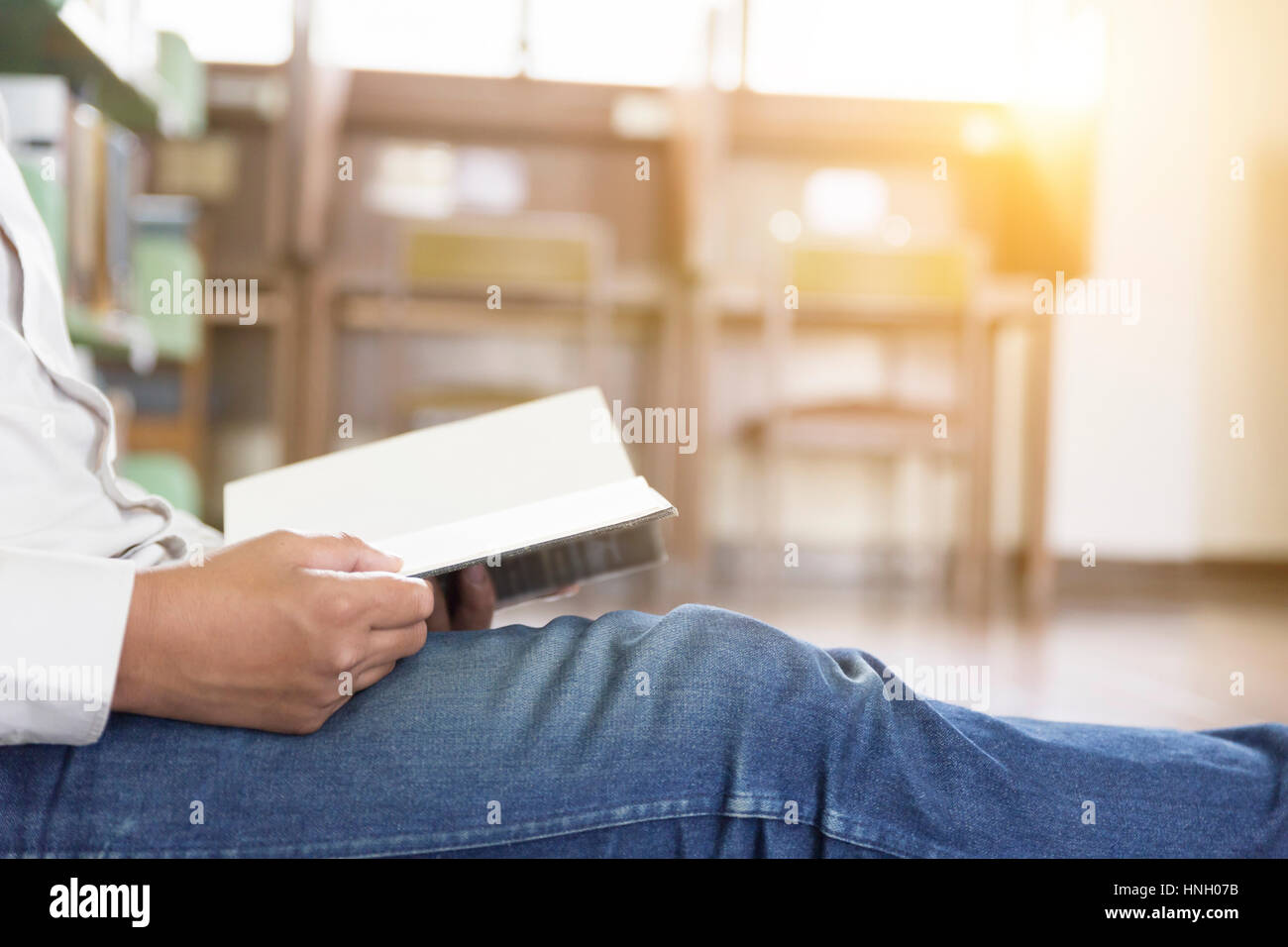 man sitting and reading book on floor in aisle in library Stock Photo ...