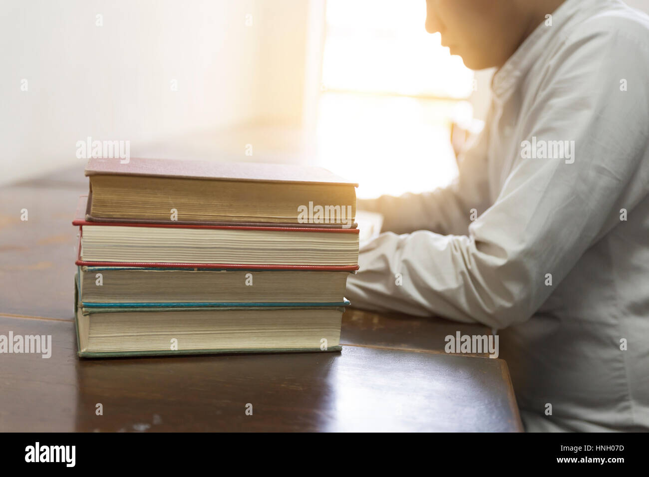 man reading book with textbook stack on wooden desk in library Stock ...